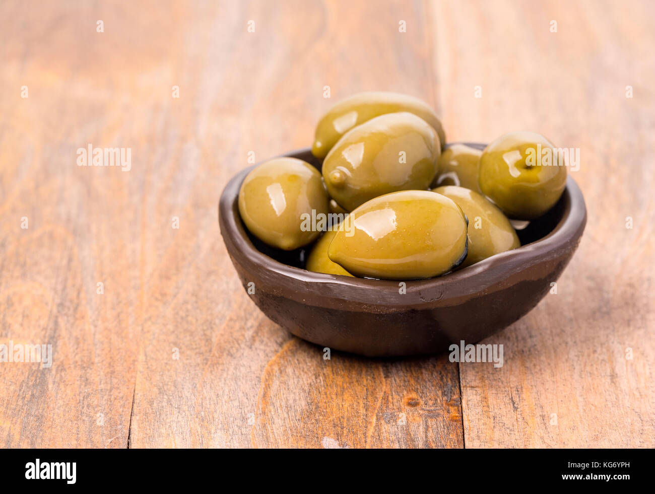 giant green olives in olive bowl on wood background, shallow focus ...