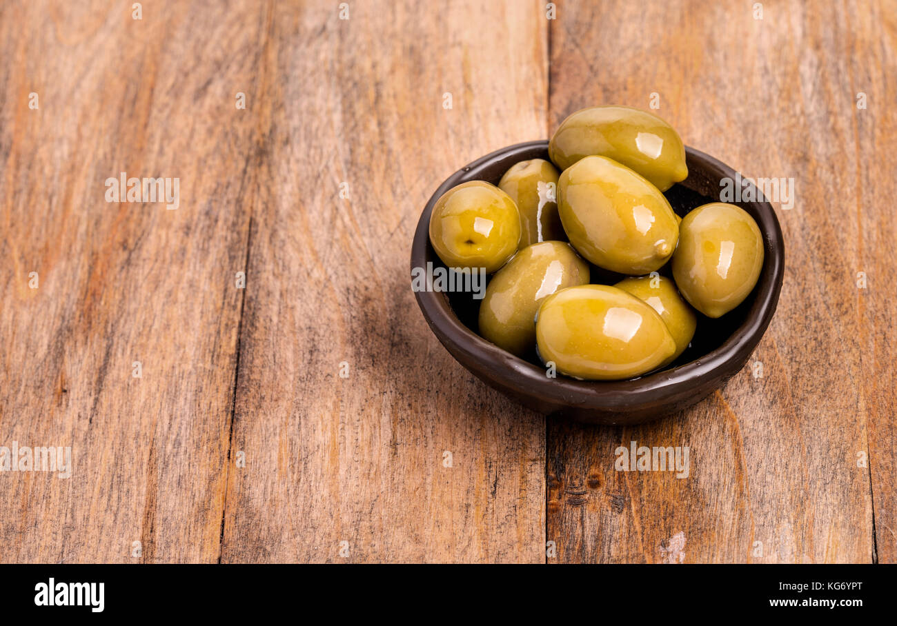 giant green olives in olive bowl on wood background, shallow focus ...