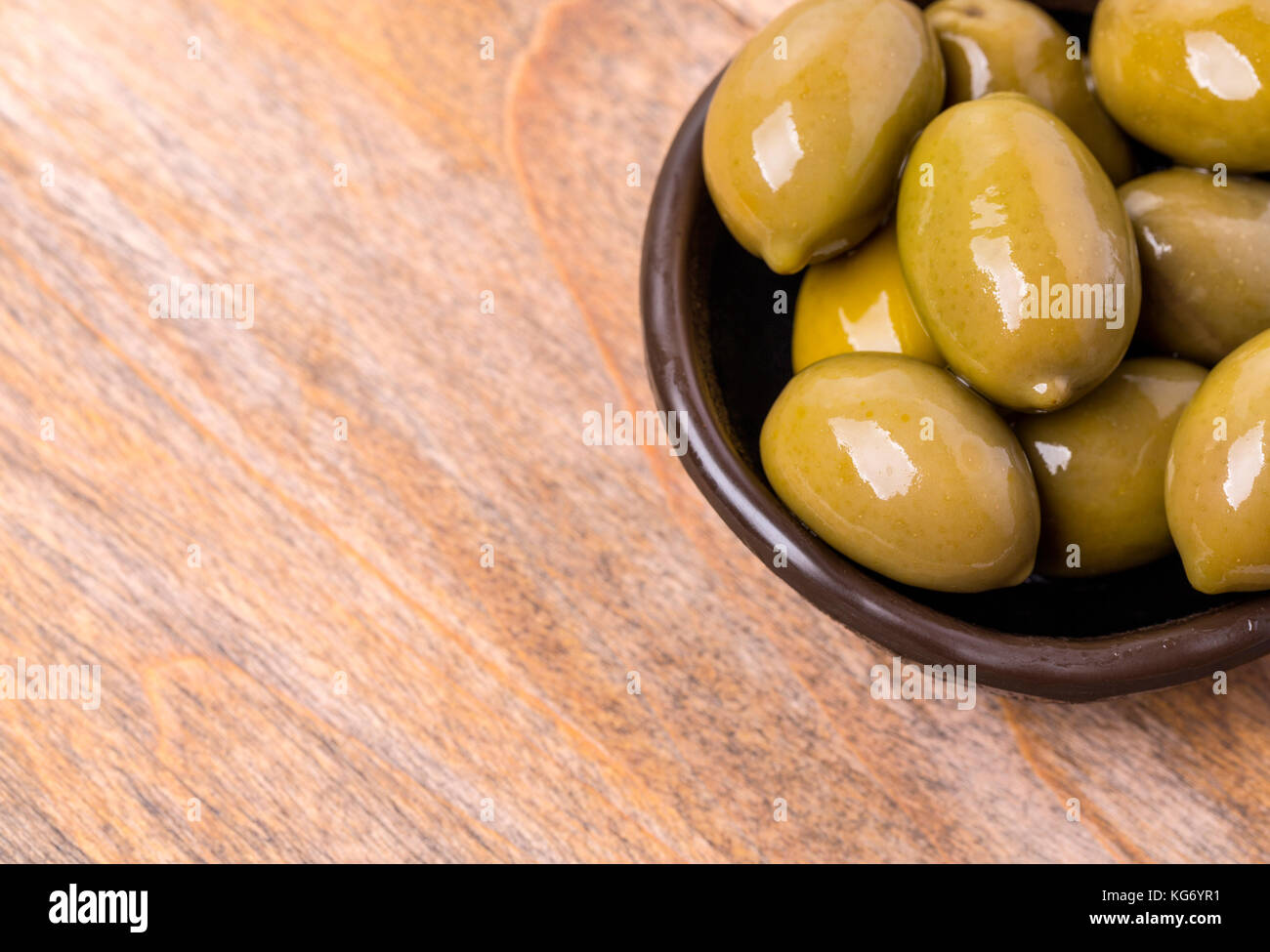 giant green olives in olive bowl on wood background, shallow focus ...