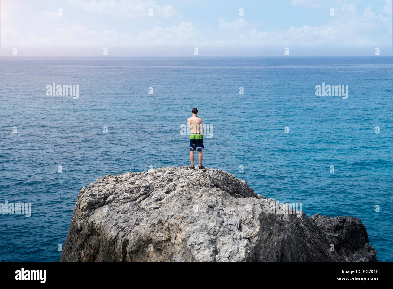 Back view of man standing on rock looking at horizon hi-res stock ...
