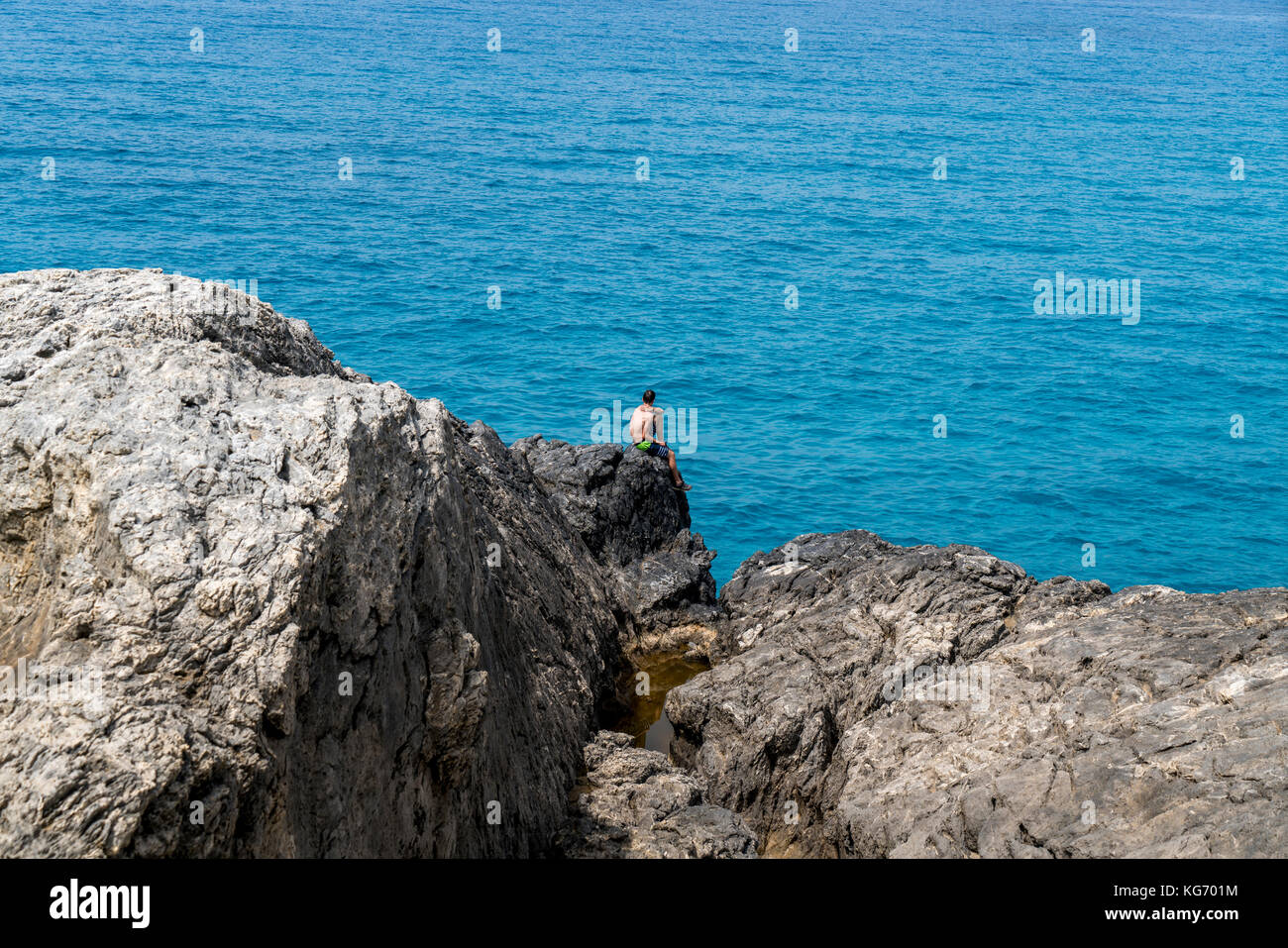 young man sitting on a cliff Stock Photo - Alamy
