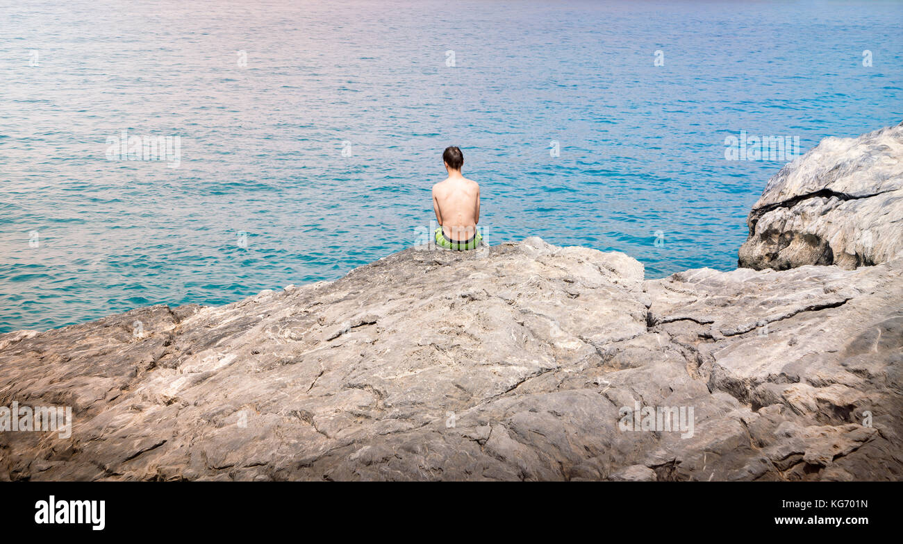 young man sitting on a cliff Stock Photo - Alamy