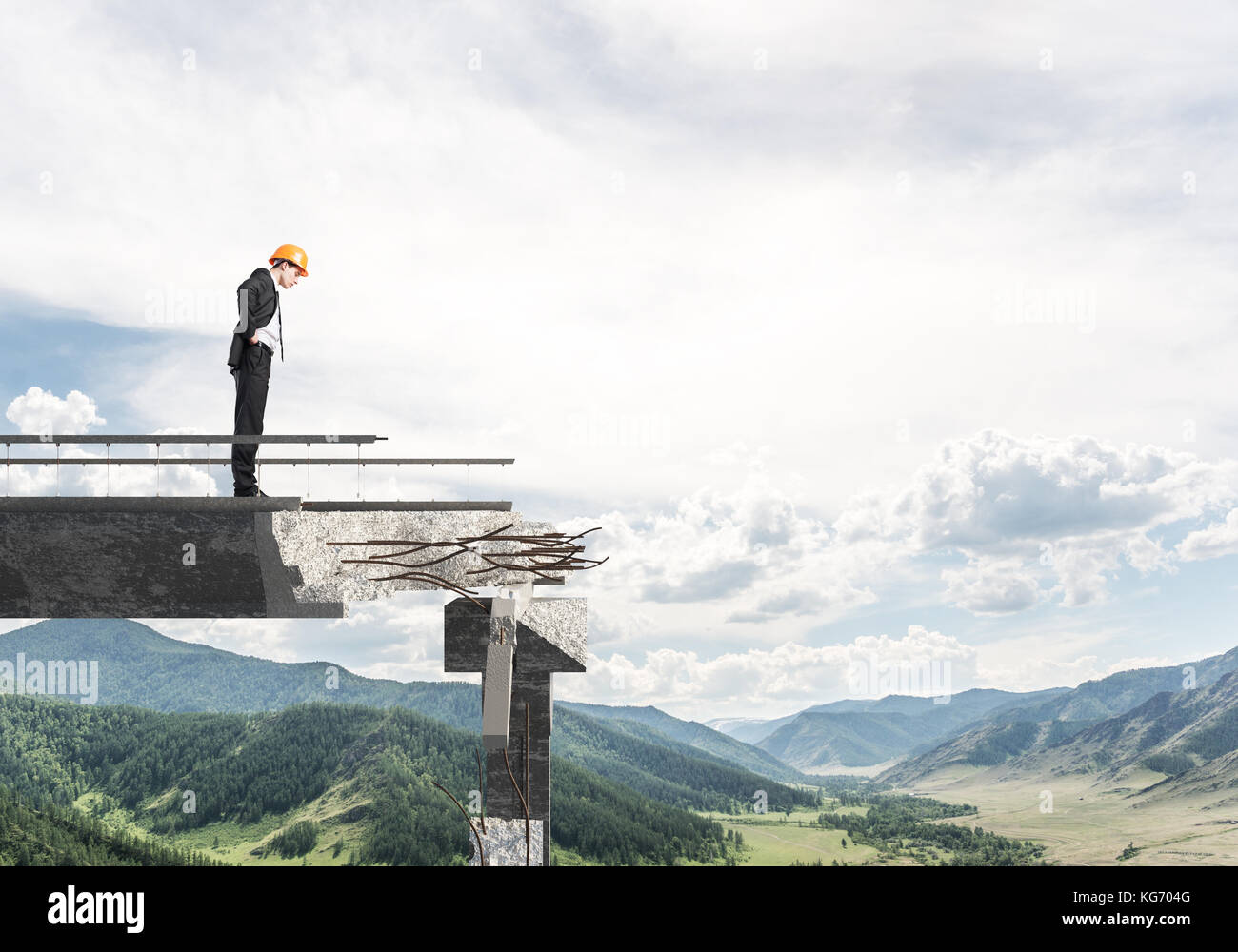 Young engineer in suit and helmet looking down while standing on broken ...
