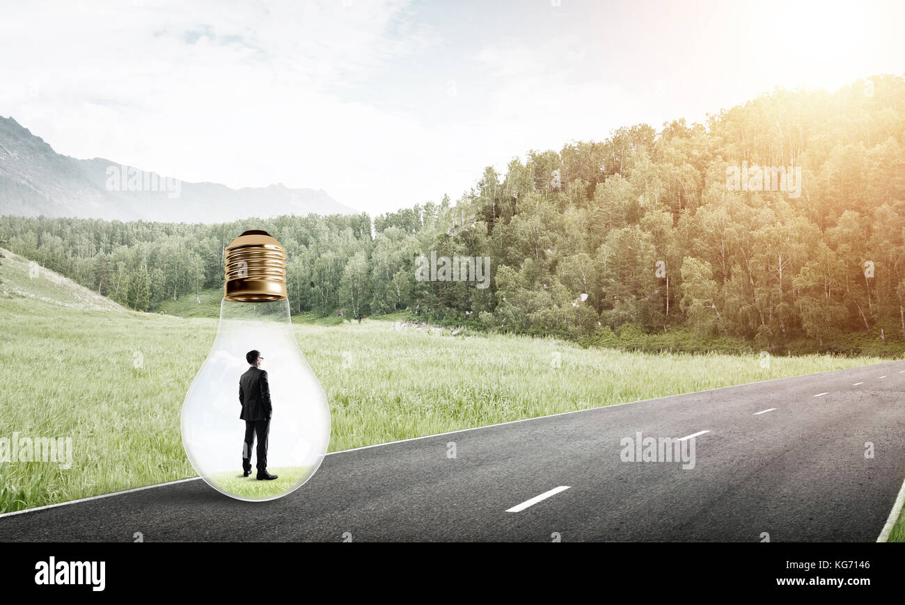 Young businessman trapped inside of light bulb on asphalt road Stock ...