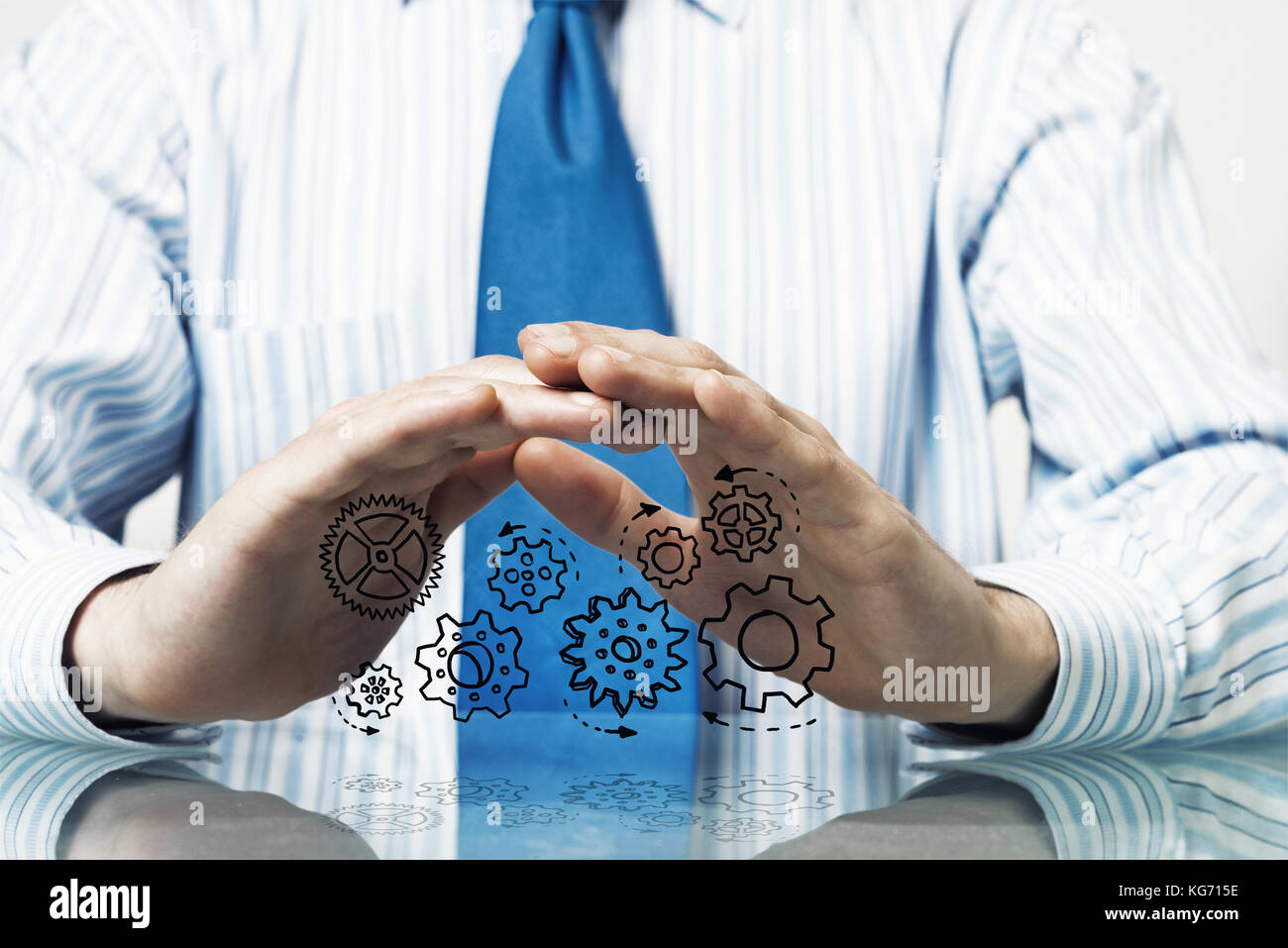 Close up of businessman sitting at table and protecting gear mechanism ...