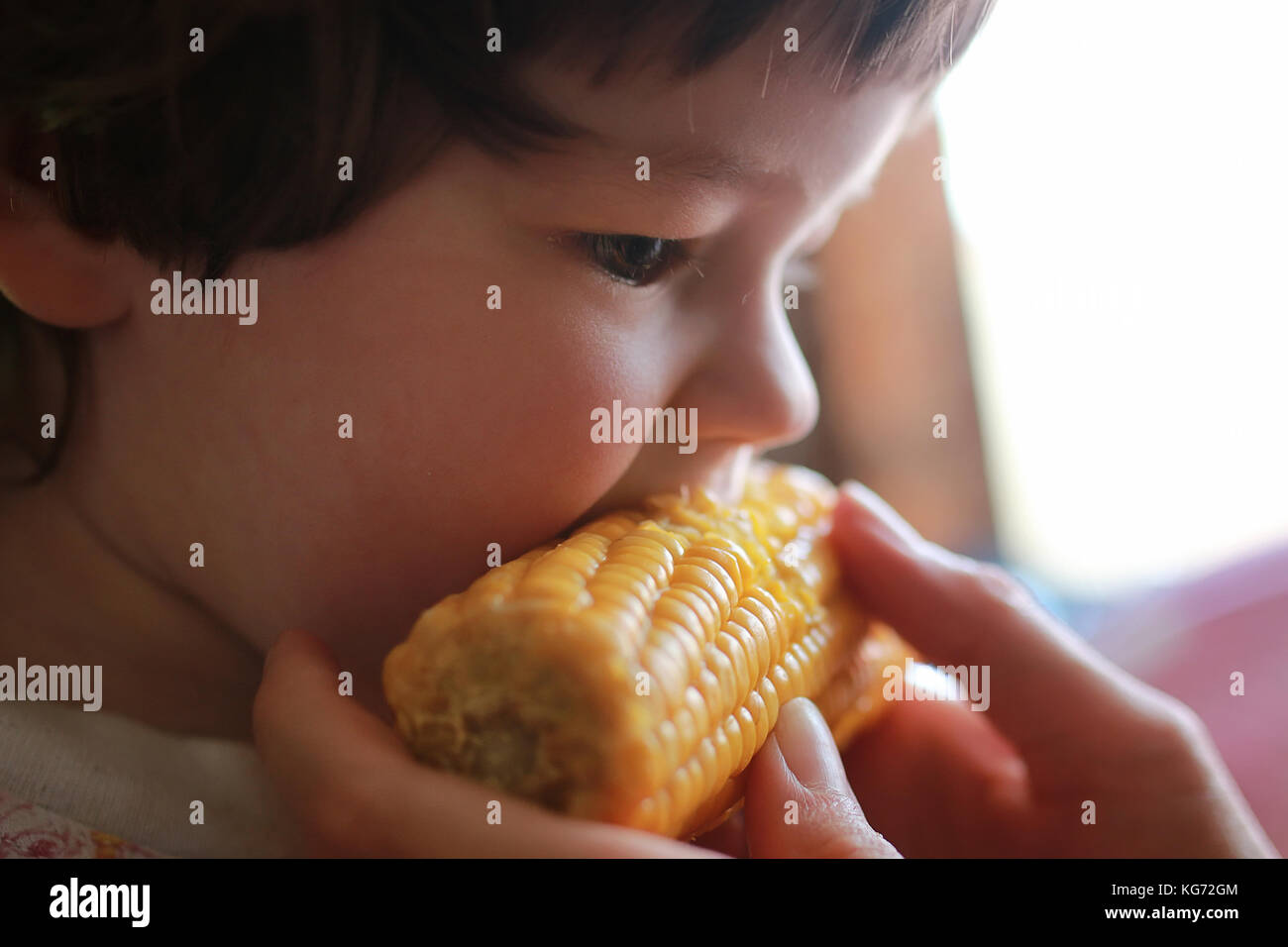 little boy eats greedily biting corn grain Stock Photo - Alamy