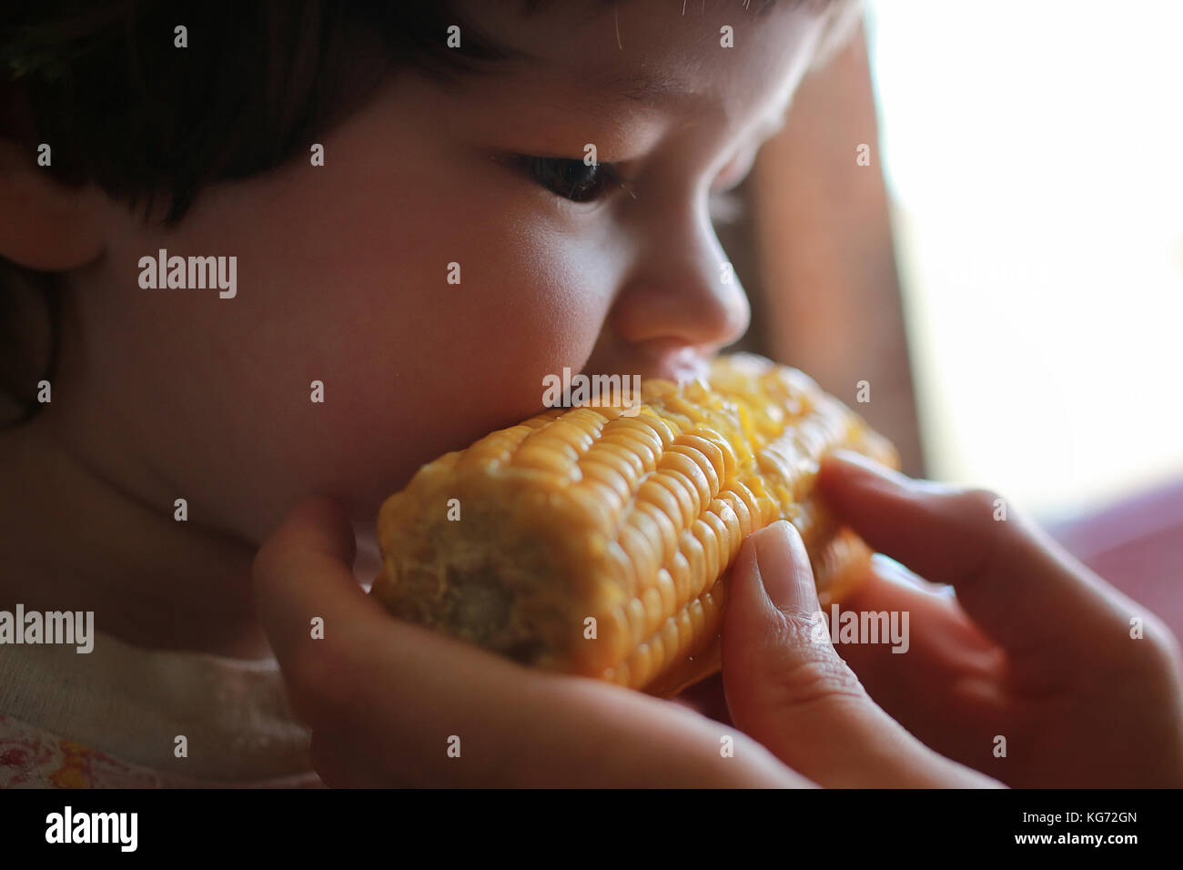 little boy eats greedily biting corn grain Stock Photo - Alamy