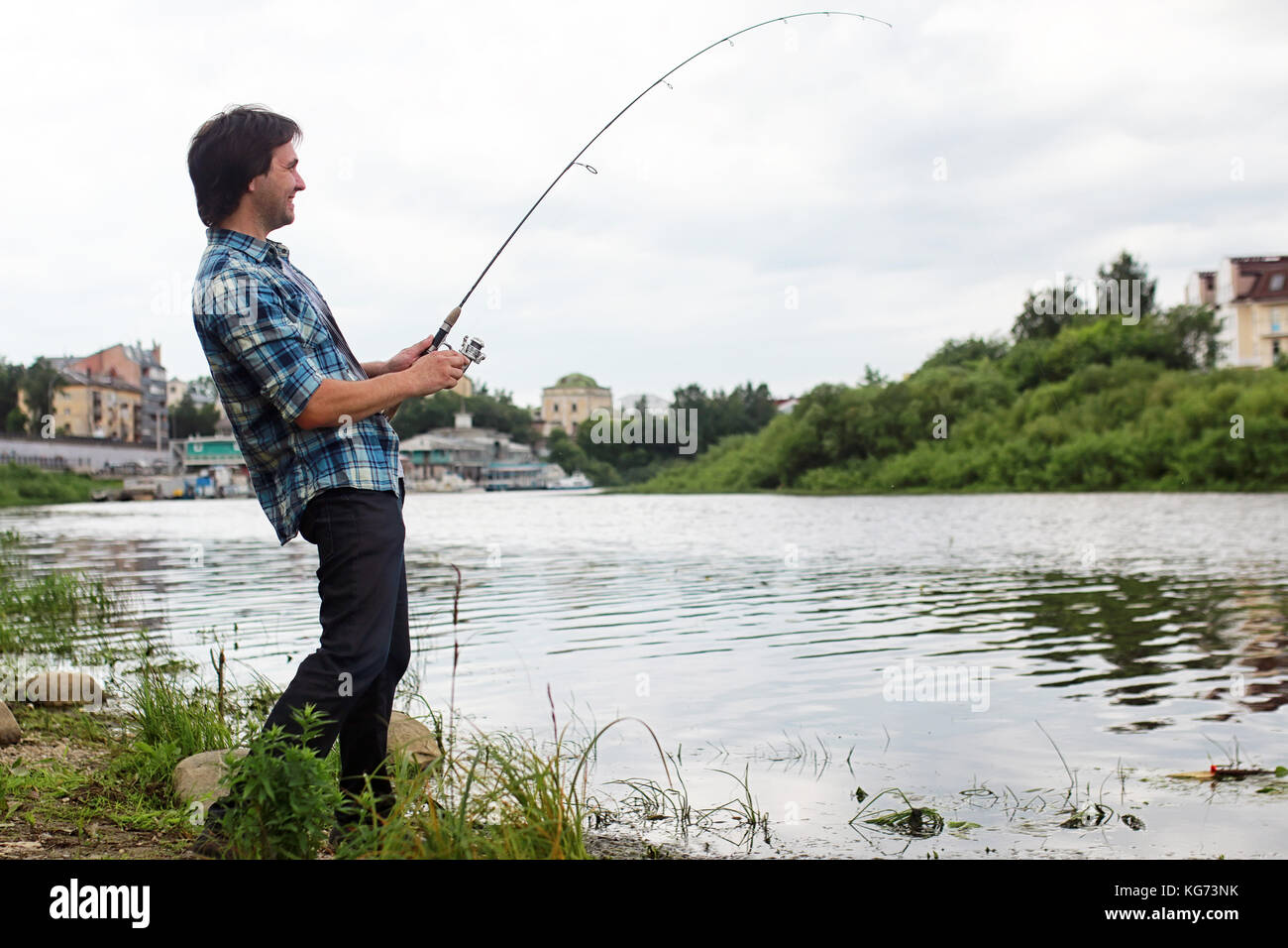 A man with a beard is fishing for spinning in the river Stock Photo - Alamy