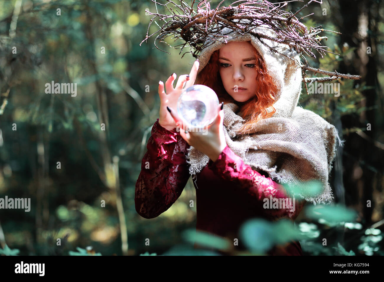 The red-haired witch holds a ritual with a crystal ball in the forest ...