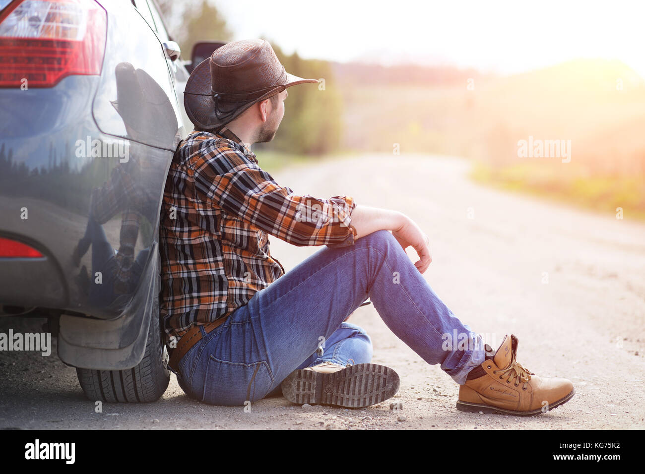 Man is sitting on the road by the car Stock Photo - Alamy