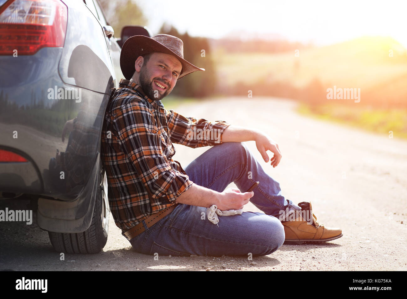 Man is sitting on the road by the car Stock Photo - Alamy