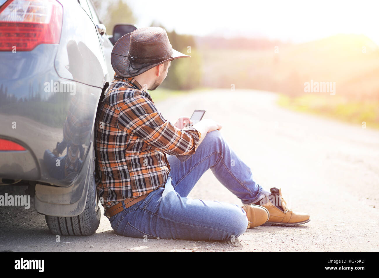 Man is sitting on the road by the car Stock Photo - Alamy