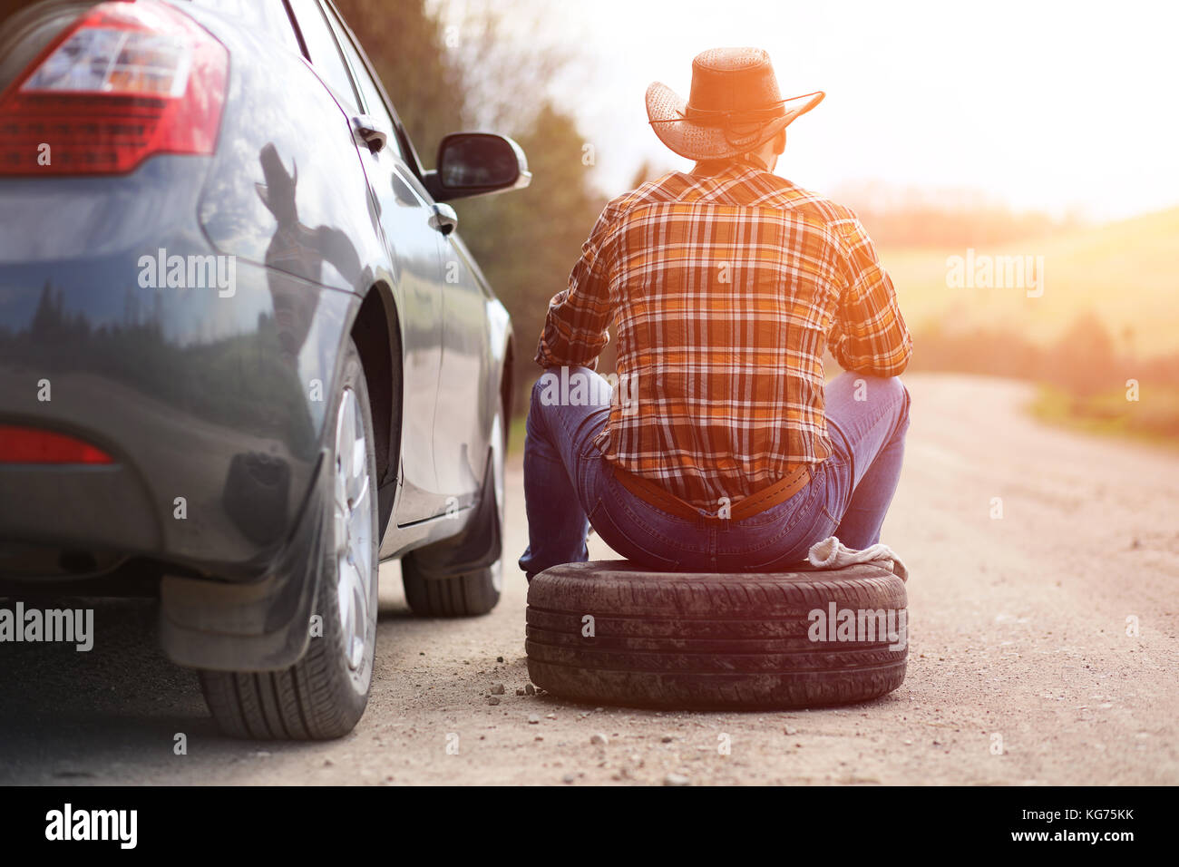 Man is sitting on the road by the car Stock Photo - Alamy