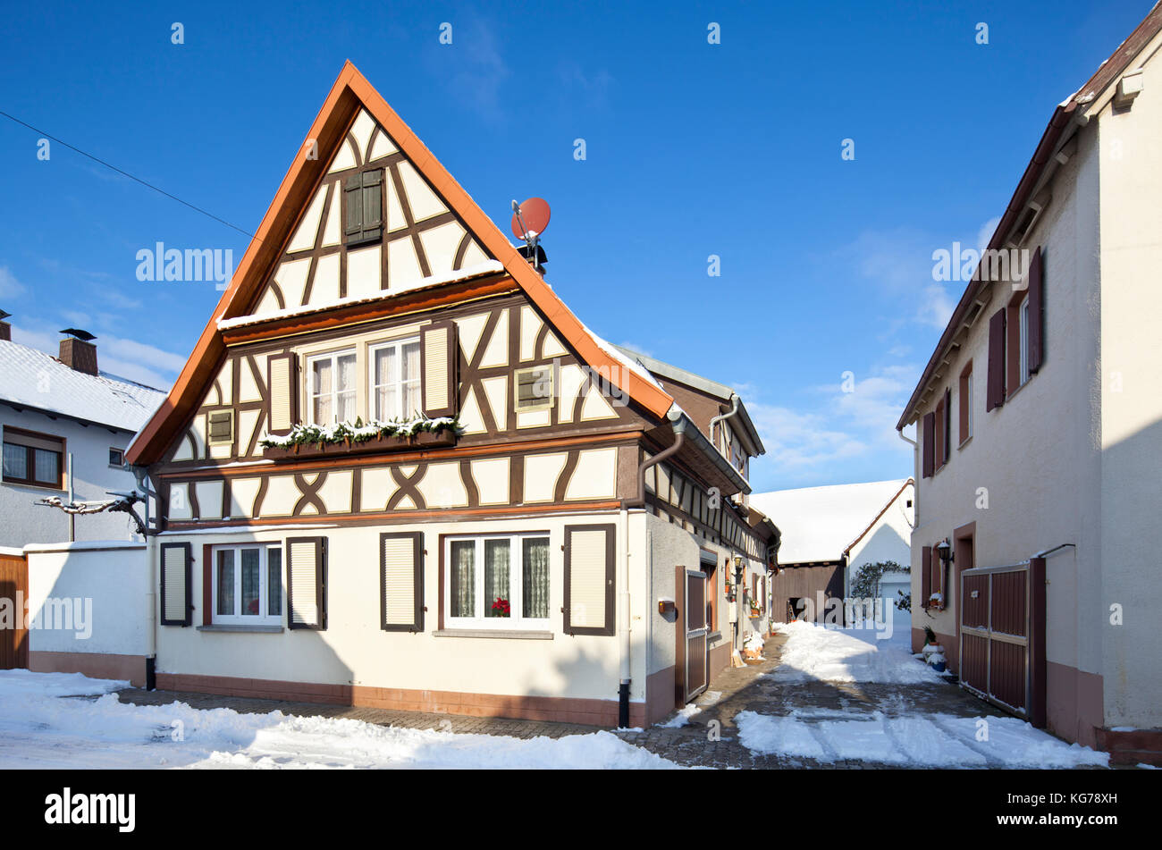 A half-timbered house in a small German village with snow and blue sky ...