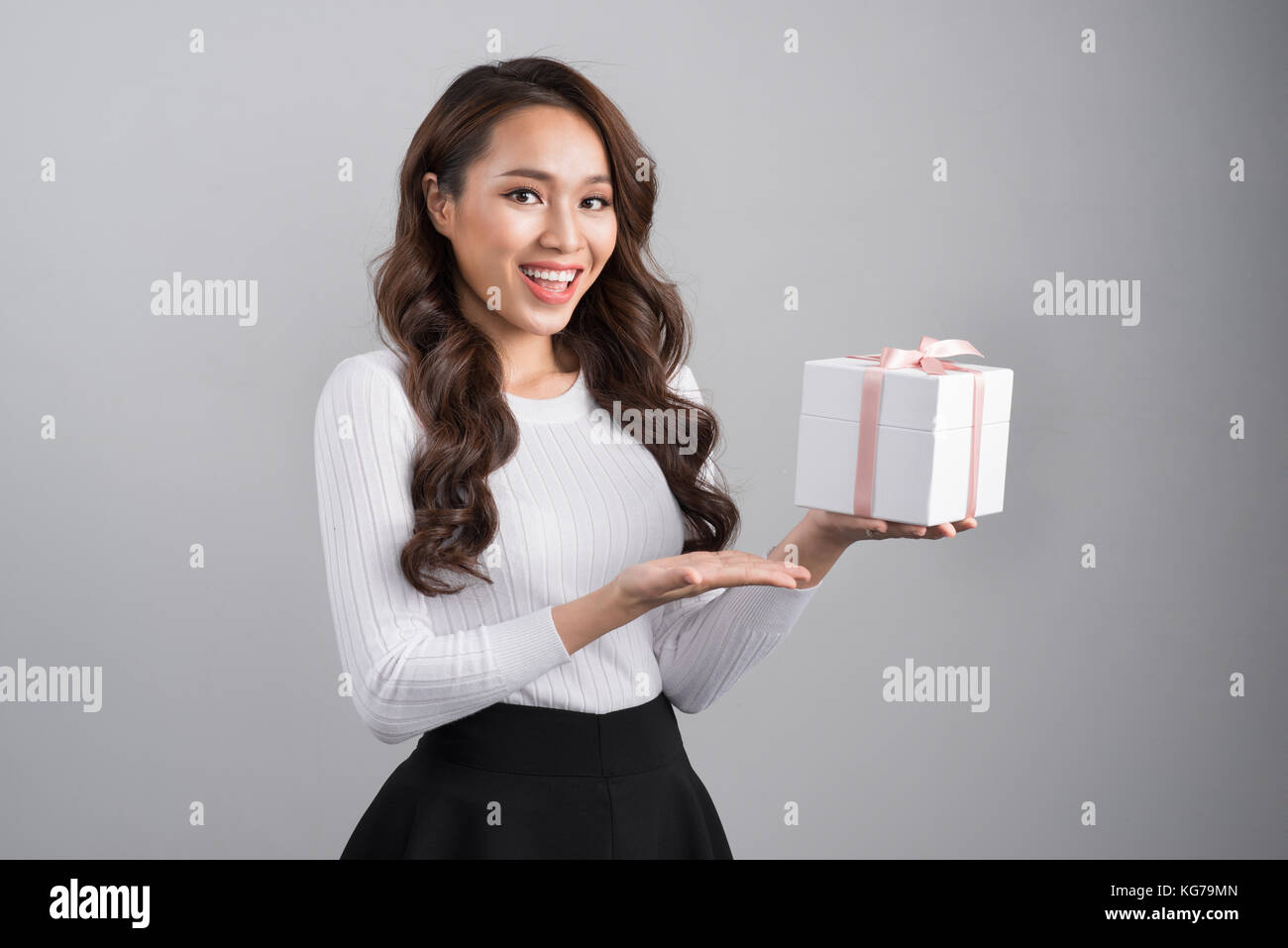 Happy young asian woman giving gift box over gray background Stock ...