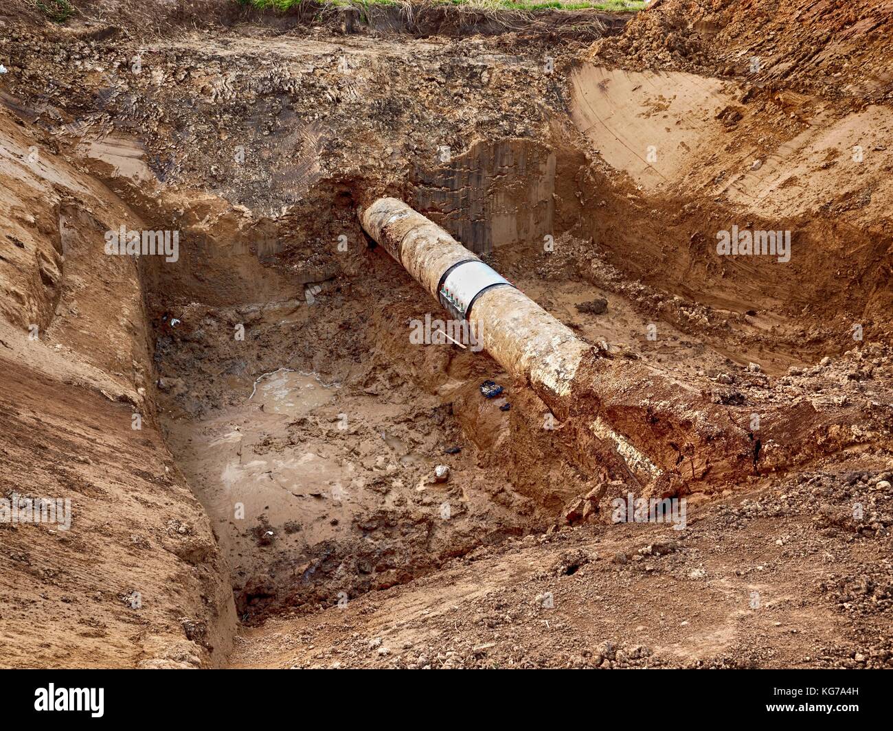 Excavation pit. Old drink water pipe with stainless repairing sleeve ...