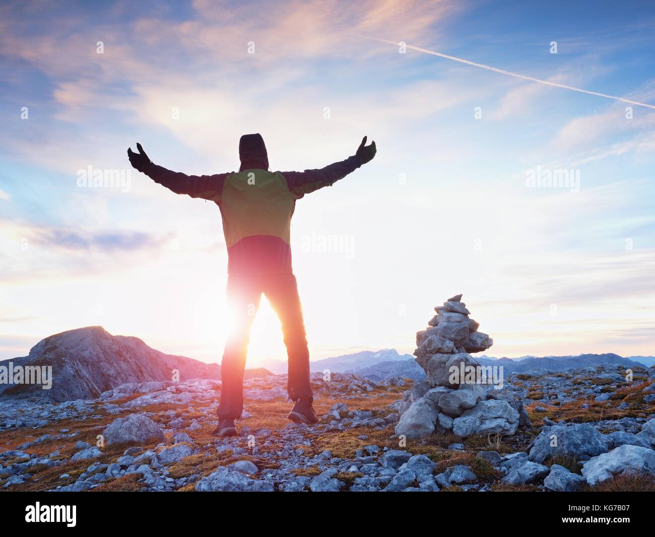 Tourist guide at stocked stones on Alps peak. Strong hiker enjoy sunset ...