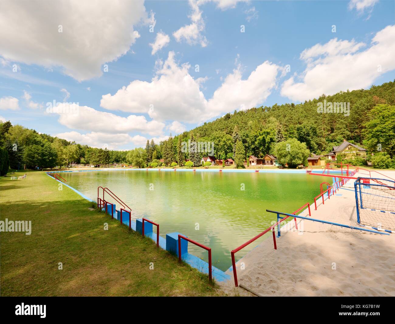 Outdoor swimming pool with ladder, springboard and grass side. Fresh ...