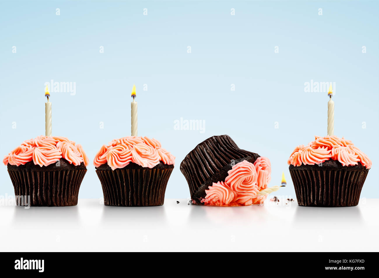 Smashed cupcake in row of cupcakes with candles on blue background ...