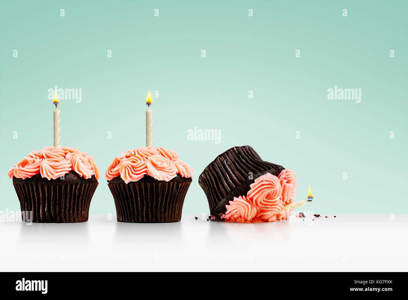 Smashed cupcake in row of cupcakes with candles on green background ...