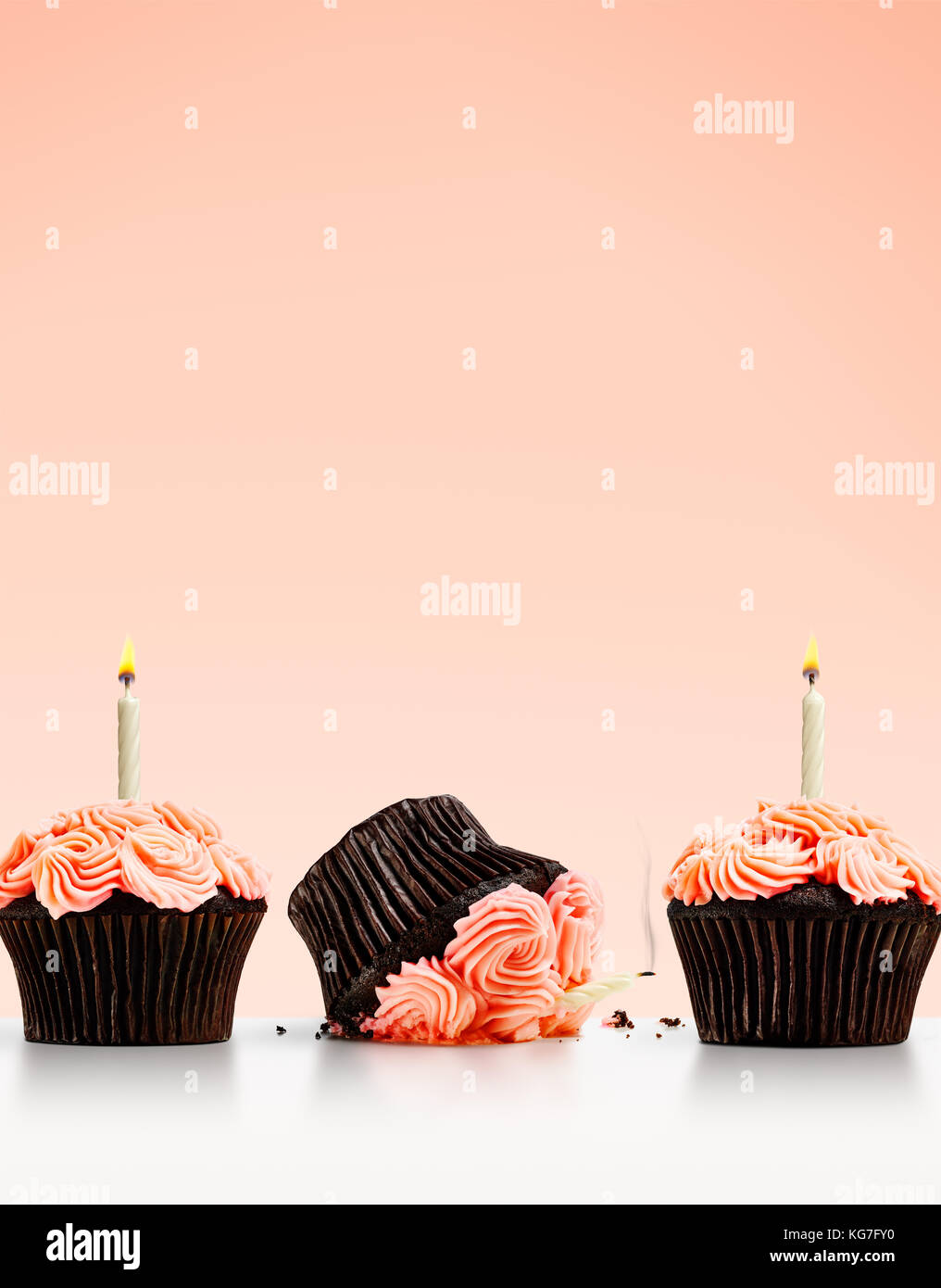 Smashed cupcake in row of cupcakes with candles on pink background ...