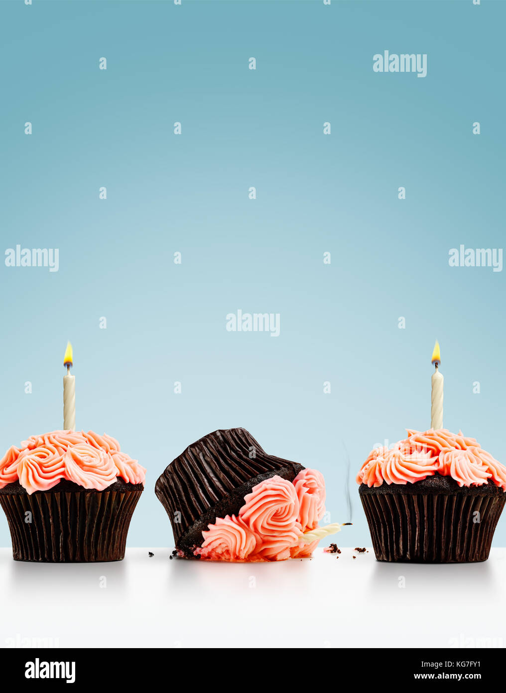 Smashed cupcake in row of cupcakes with candles on blue background ...