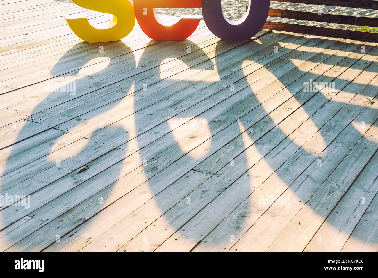 The word SEO by large colored letters creating a shadow on the wooden ...