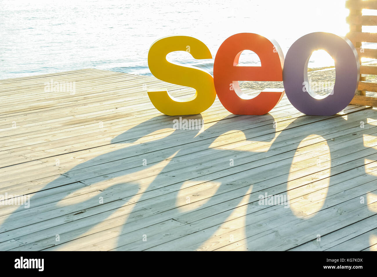 The word SEO by large colored letters creating a shadow on the wooden ...
