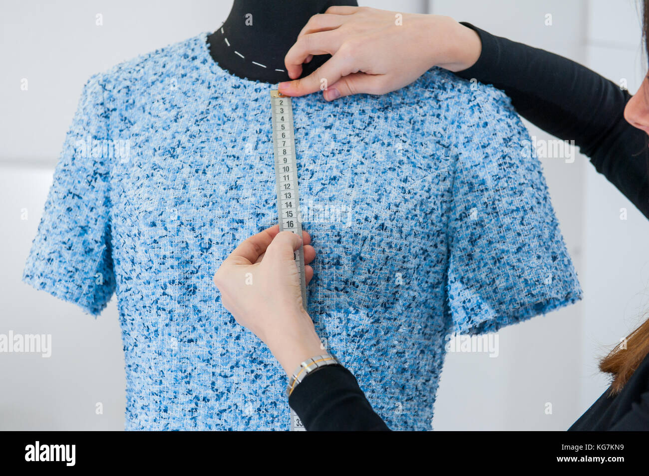 Female seamstress prepares dress to the fitting and takes measurements ...