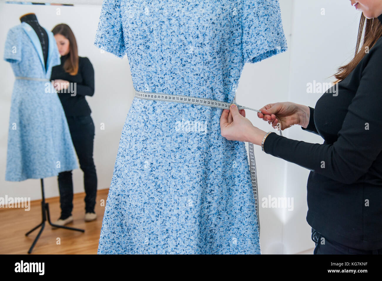 Female seamstress prepares dress to the fitting and takes measurements ...