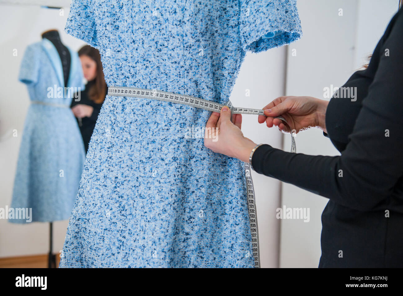 Female seamstress prepares dress to the fitting and takes measurements ...