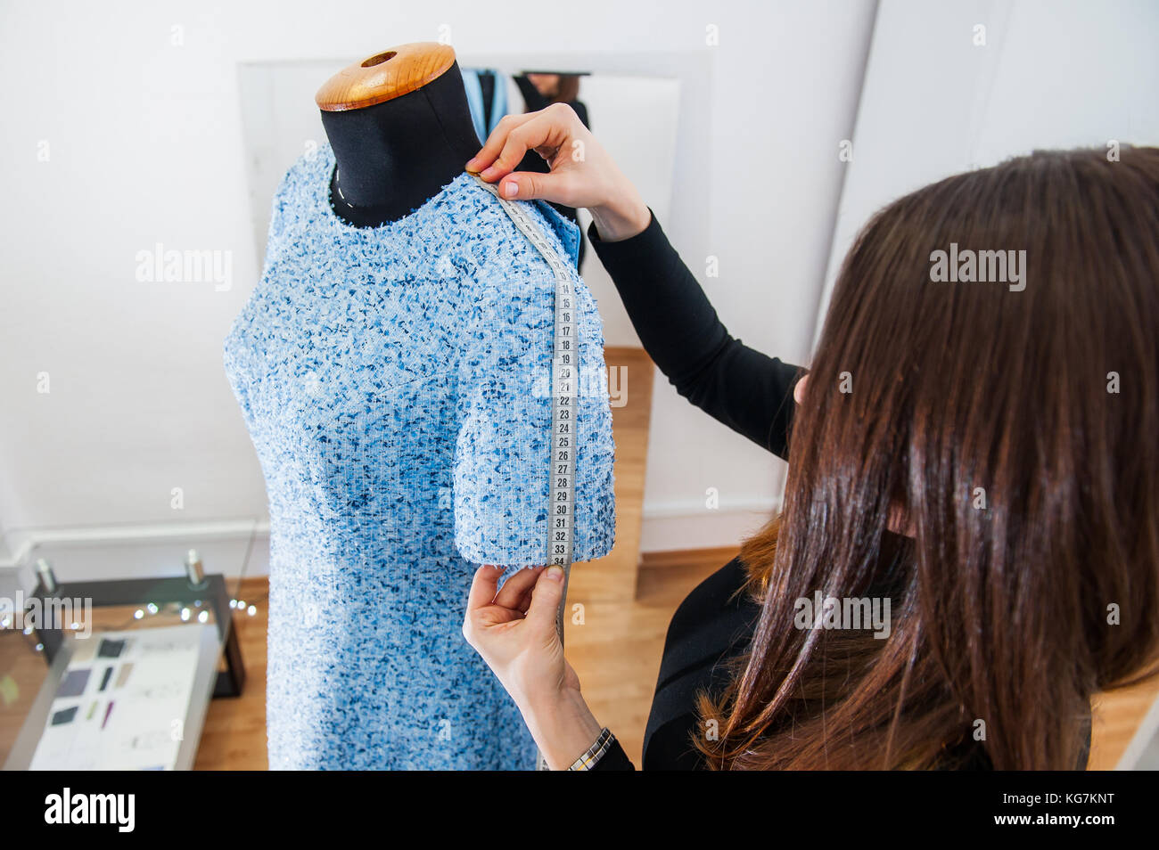 Female seamstress prepares dress to the fitting and takes measurements ...