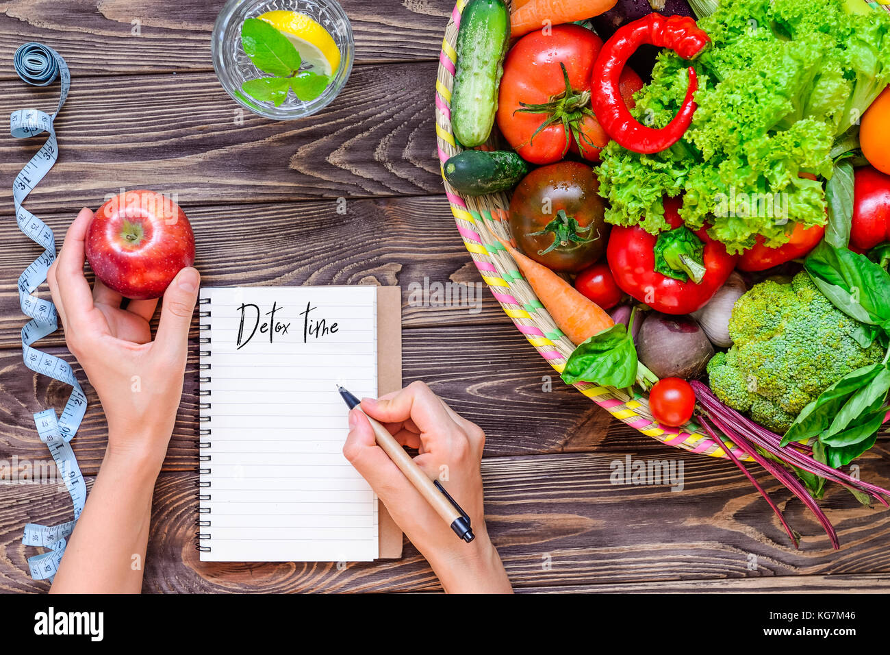 Female hands make notes in diet book on the wood table with Basket of ...