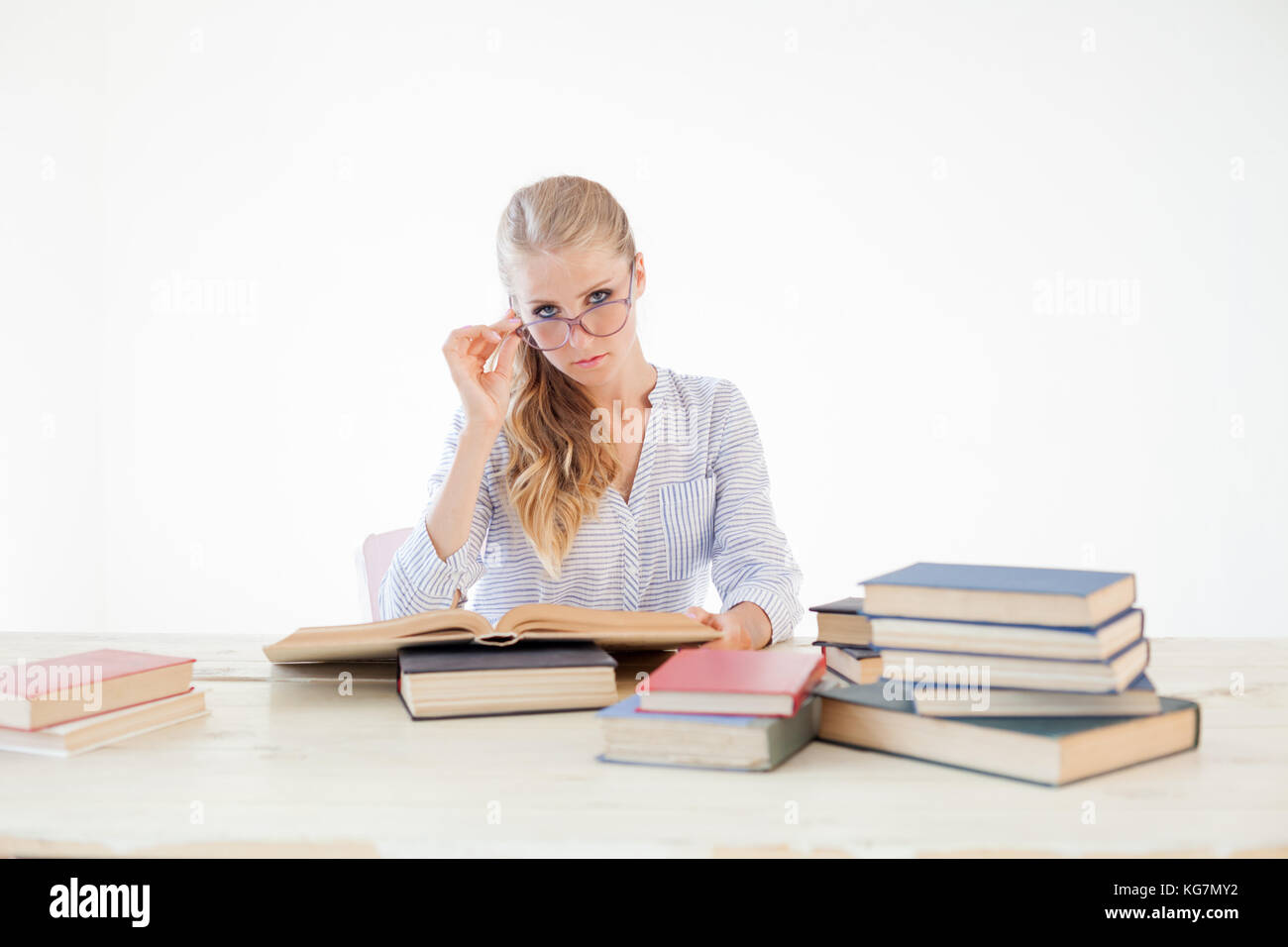 female teacher sitting at a table of many books Office Stock Photo - Alamy