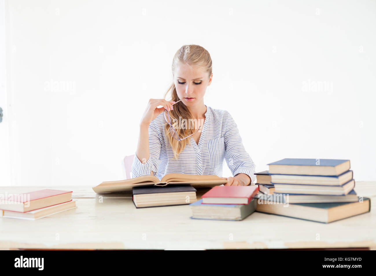 female teacher sitting at a table of many books Office Stock Photo - Alamy