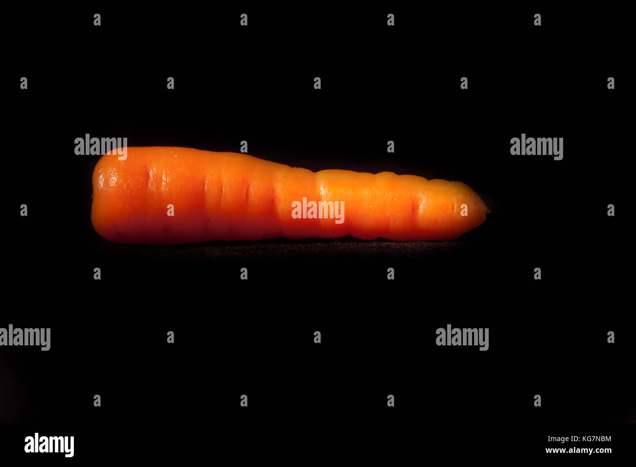 single orange carrot from the side on black background Stock Photo - Alamy