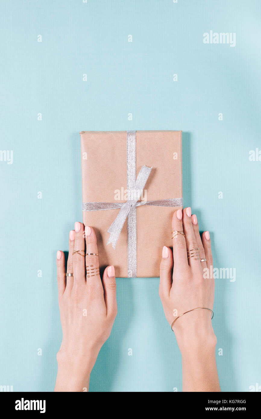 Vertical image of female hands holding a box with gift on a blue ...