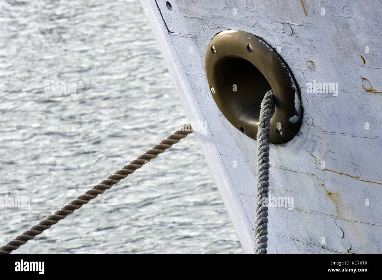 some ropes tied to a harbour wall and coming out of a brass hawsepipe ...