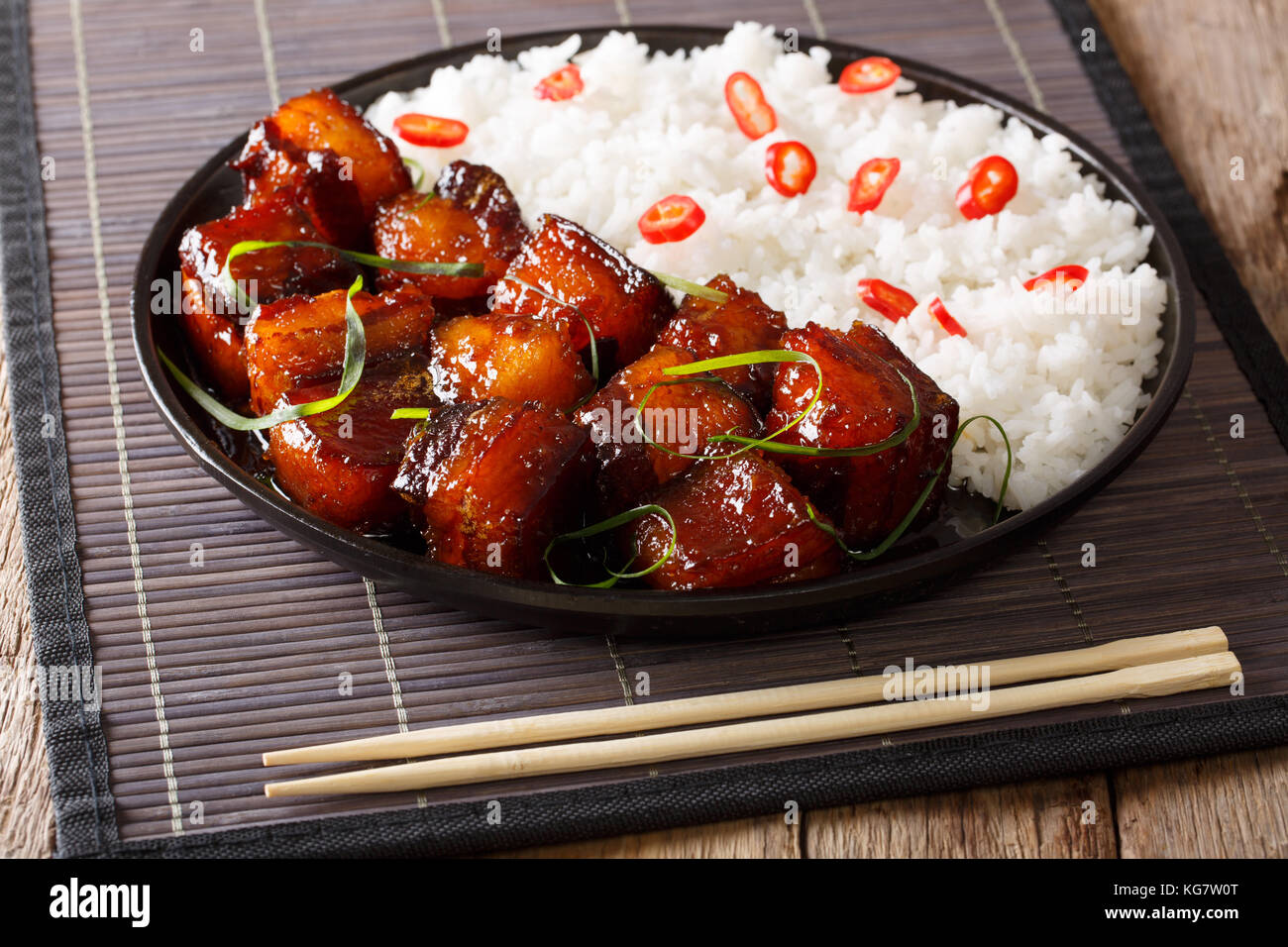 Vietnamese spicy caramel pork belly with rice closeup on a plate on a ...