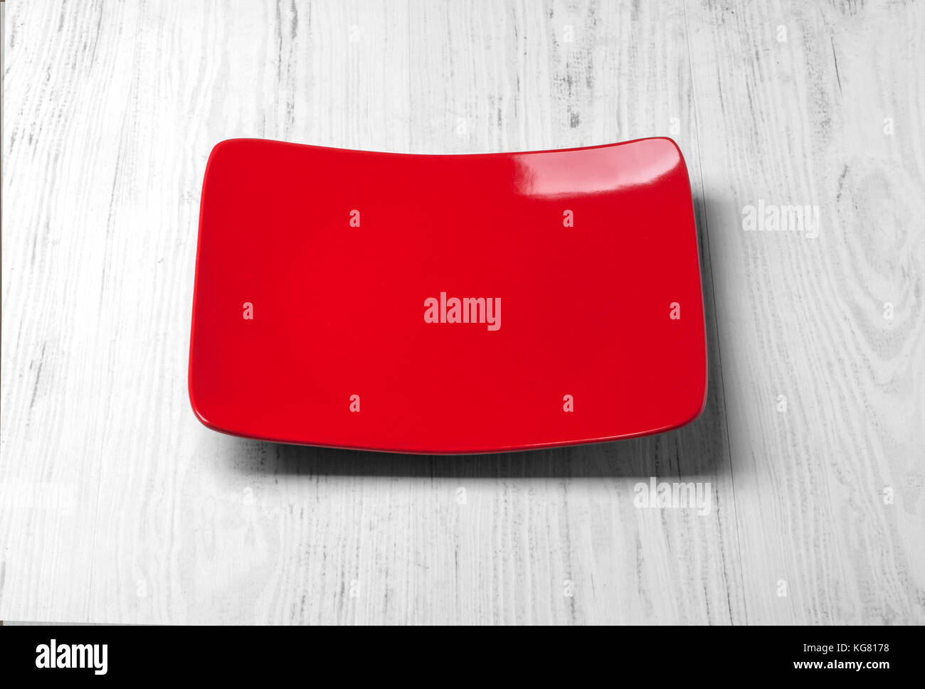 red plate on a light wooden table background Stock Photo - Alamy