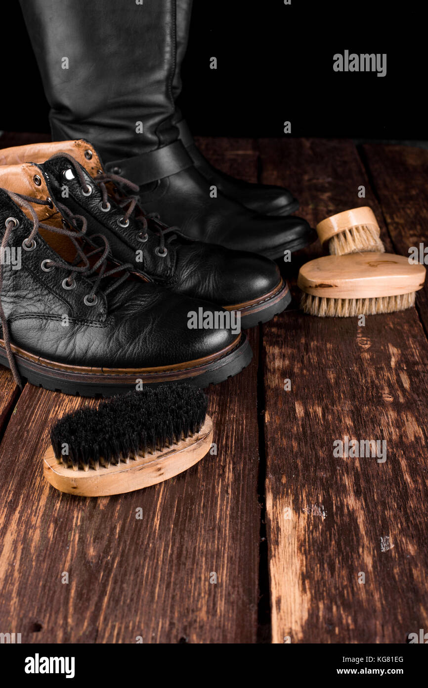 Black boots on wooden background with polishing equipment, brush and ...