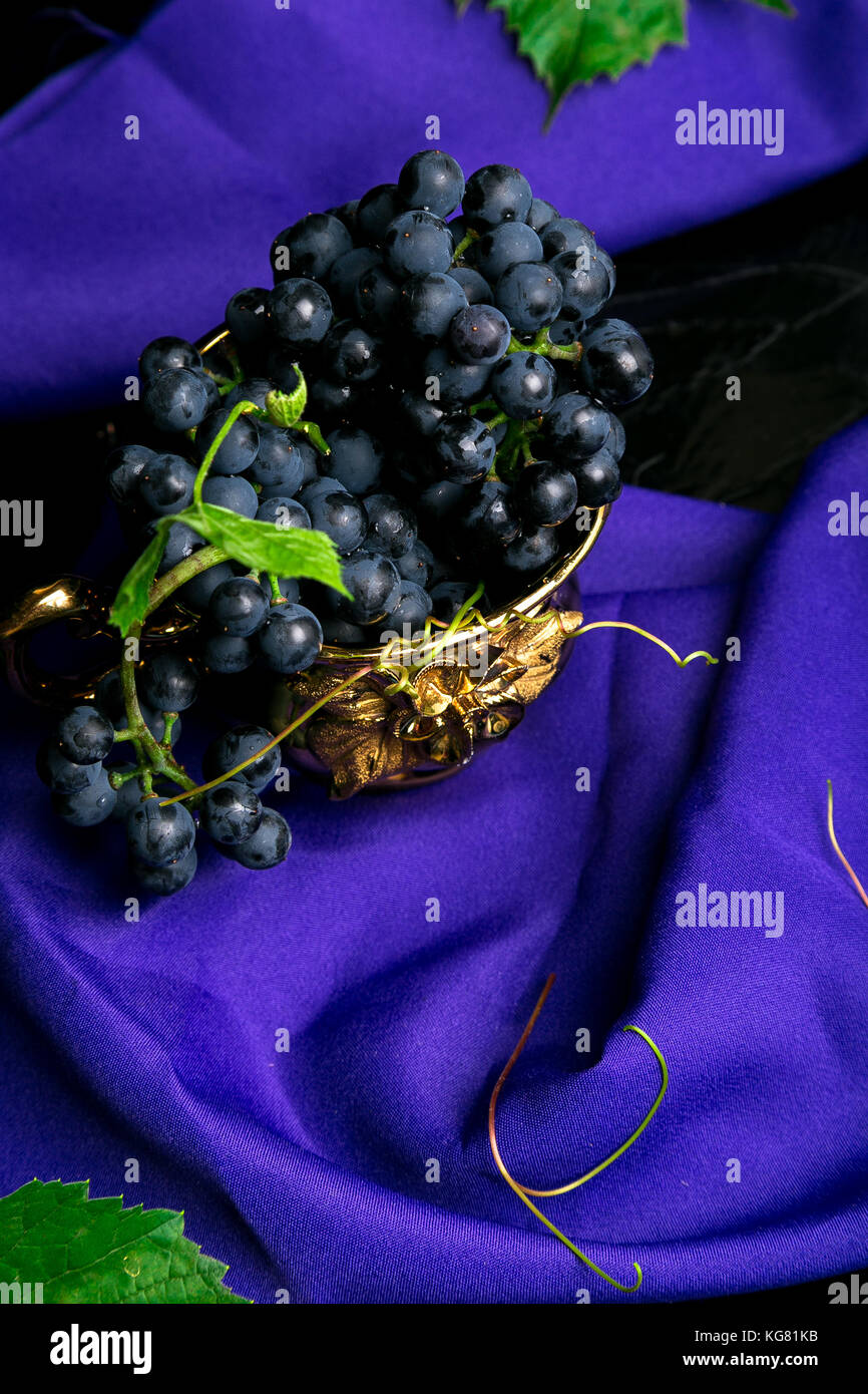 Red wine grapes in golden cup on violet background Stock Photo - Alamy