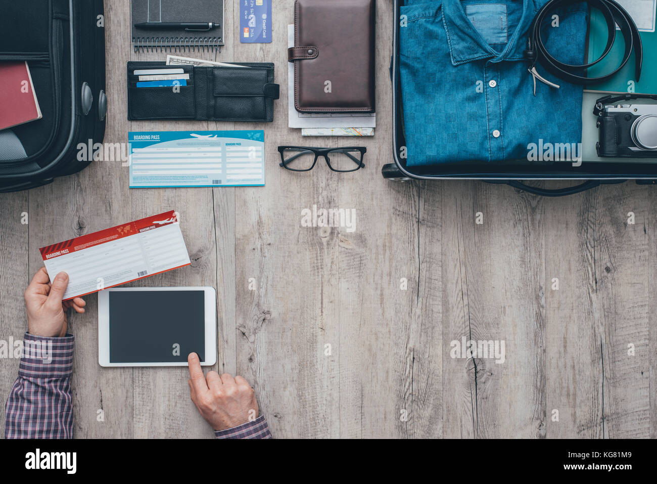 Man packing for a trip, he is using a digital touch screen tablet and ...