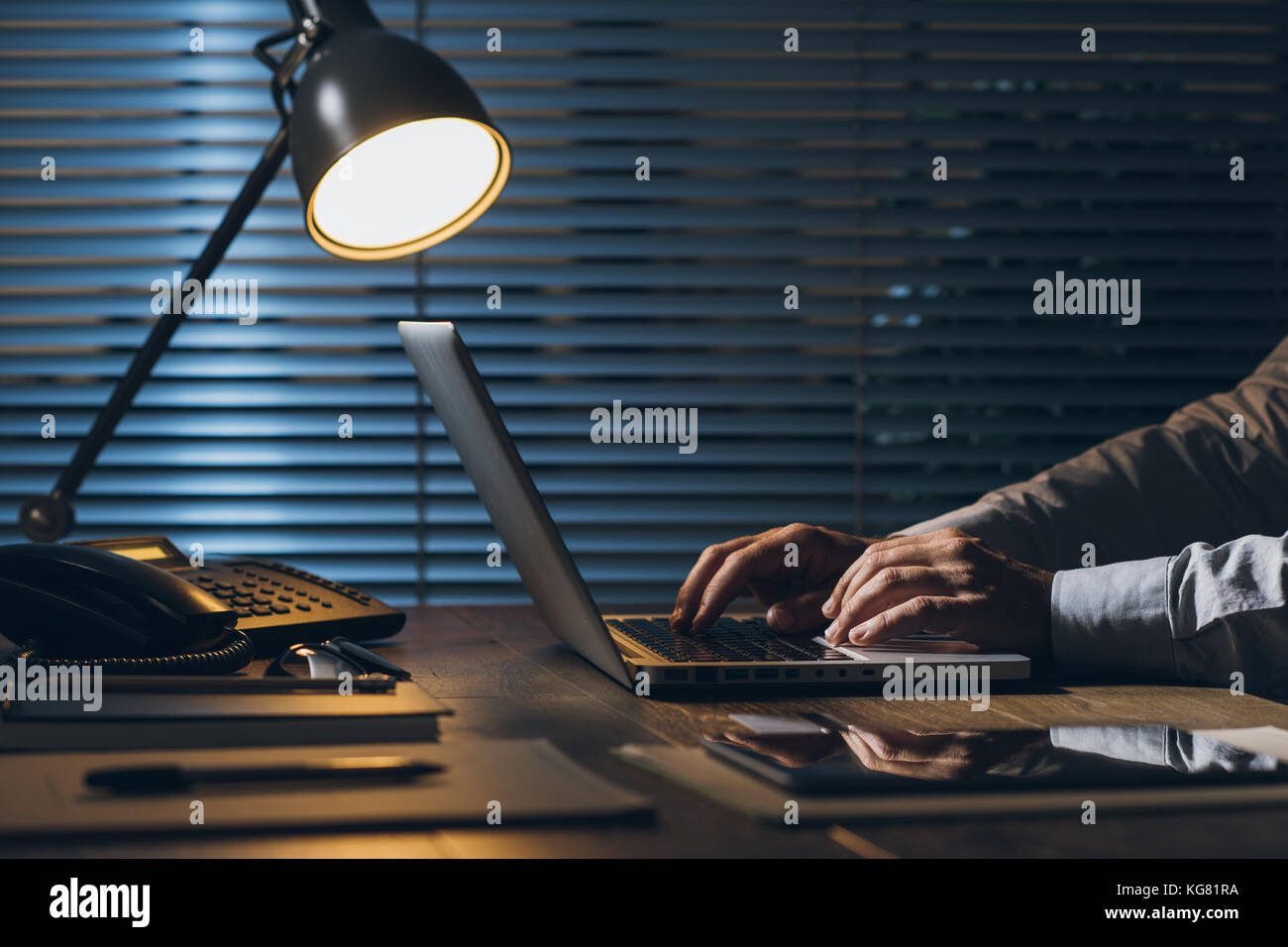 Corporate businessman working at office desk with his laptop late at ...