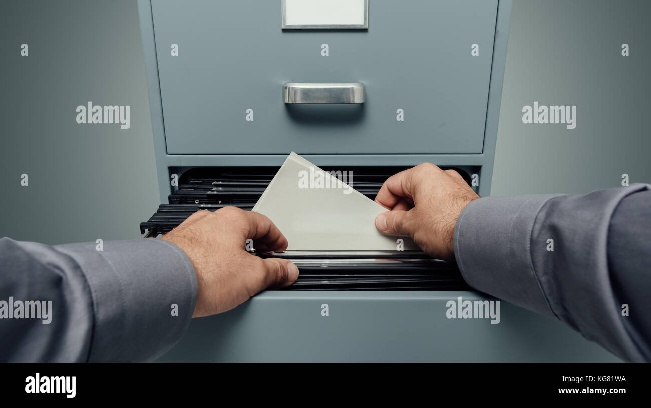Office clerk searching for files in the filing cabinet, data storage ...