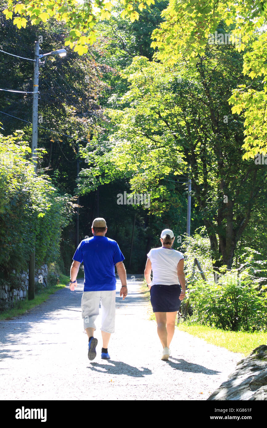 Couple taking a brisk walk on a tree-lined path on the lower levels of ...