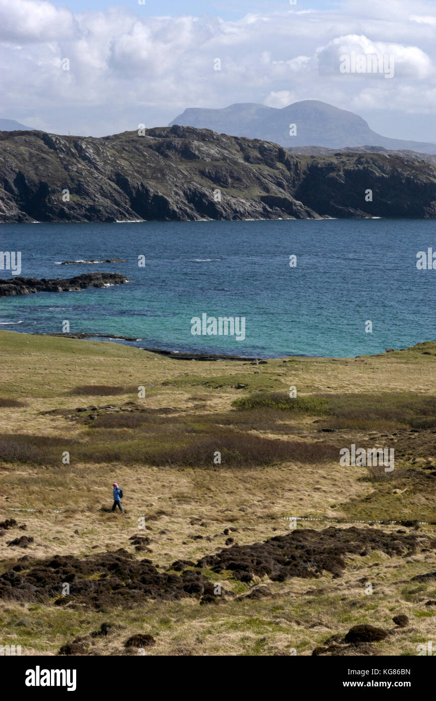 A lone hiker strolling across a barren landscape of the inhabited Handa ...