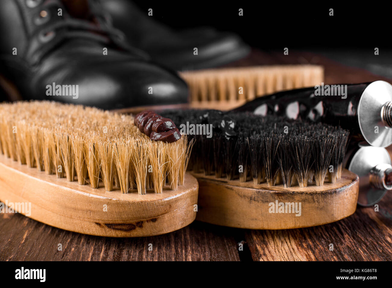 Black boots on wooden background with polishing equipment, brush and ...