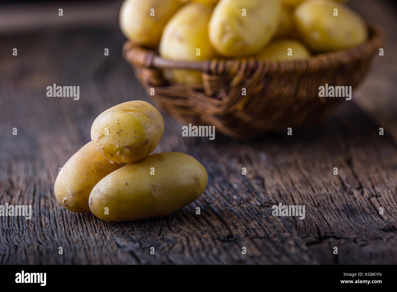 Fresh raw potatoes in basket on rustic oak board Stock Photo - Alamy