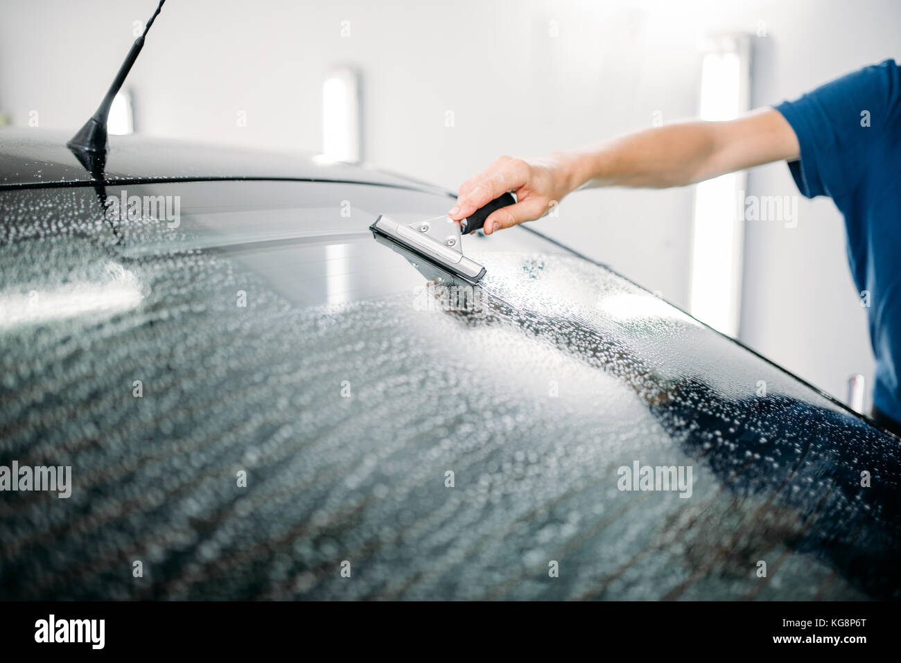 Male specialist work with window, car tinting film installation process ...